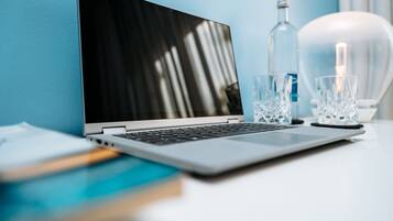 Um laptop sobre uma mesa branca, com uma parede azul ao fundo.