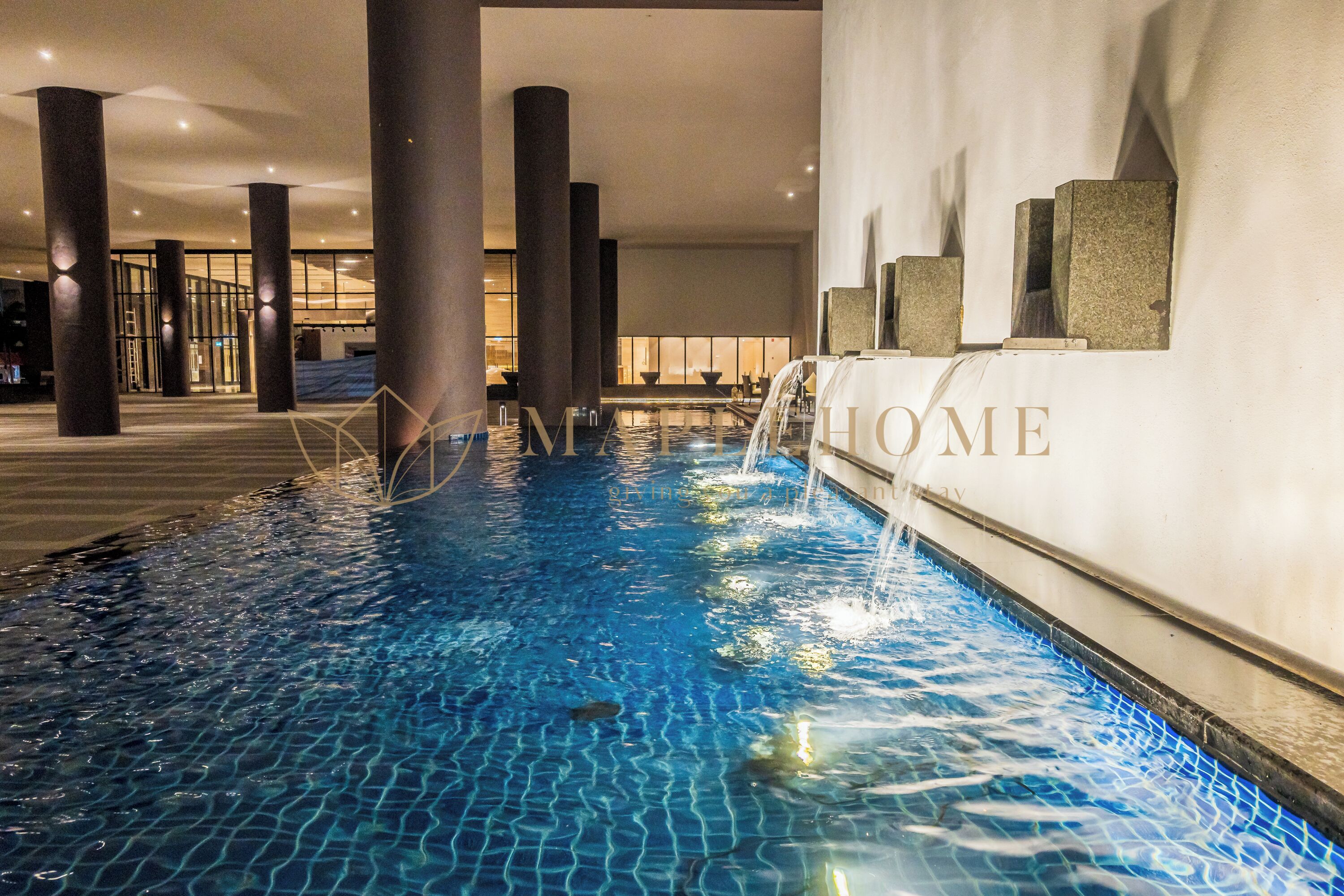 Piscina interna com água cristalina, rodeada por pilares e uma parede onde se lê "HOME".
