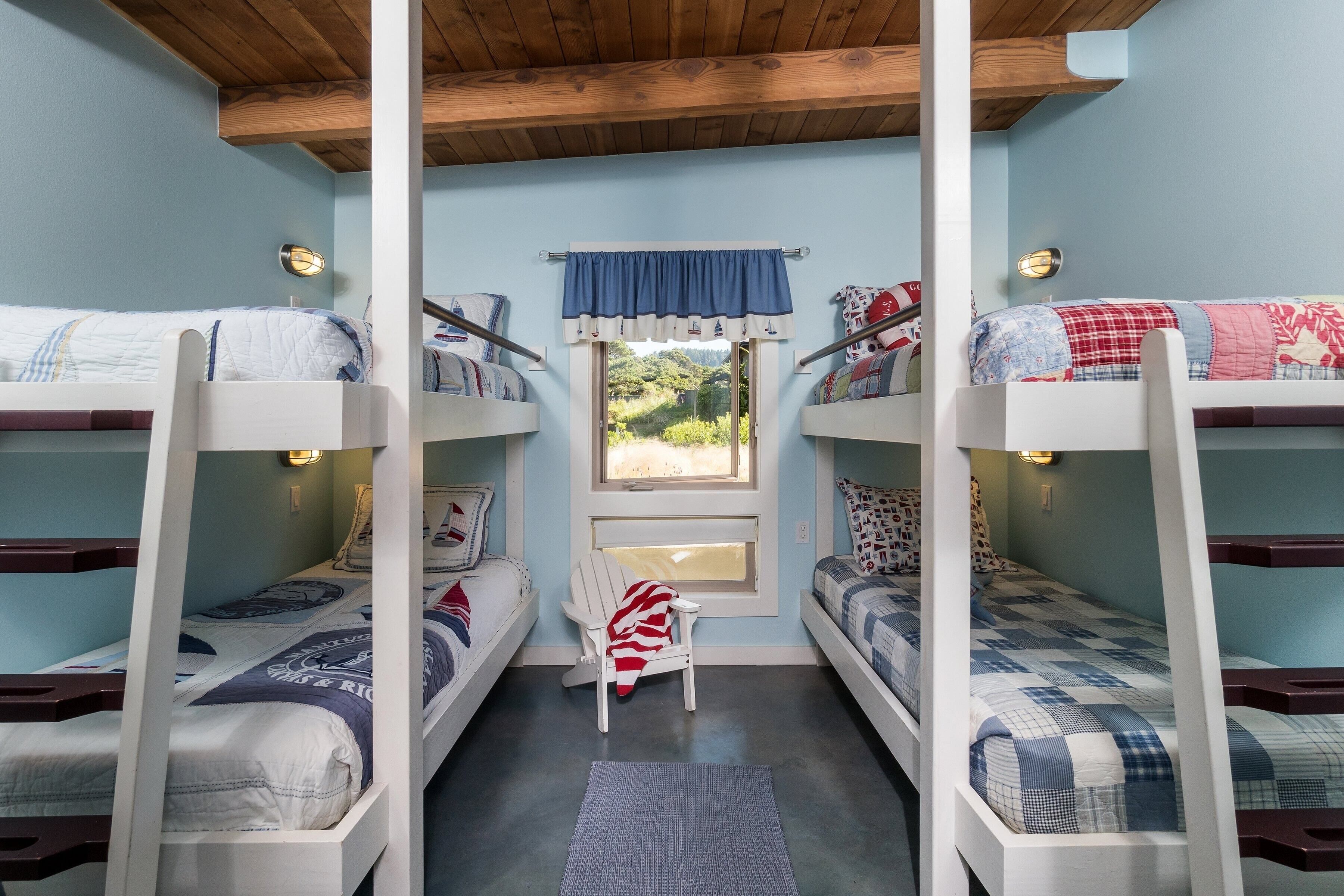 Quarto com beliche, duas camas, janela com vista e cadeira com cobertor.