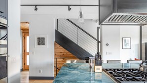 Cozinha moderna com bancada de mármore, fogão a gás e exaustor de aço inoxidável.