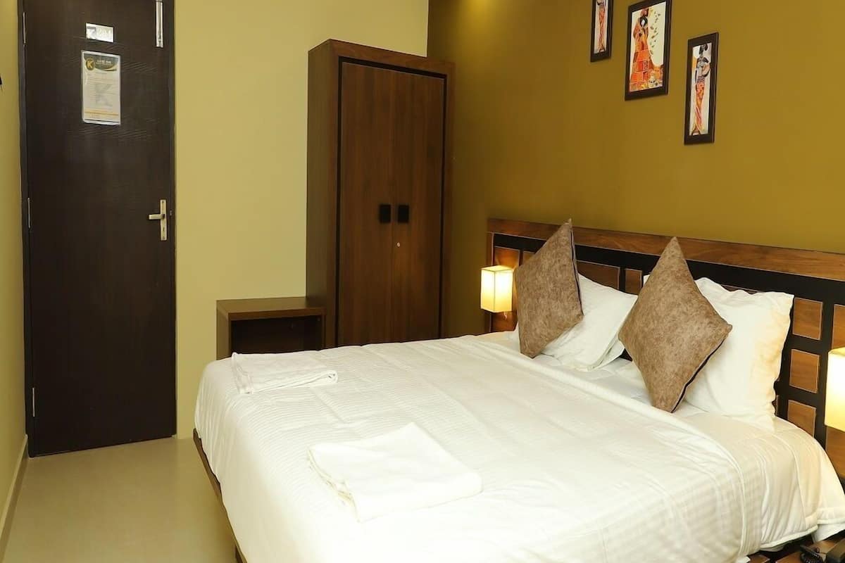 Quarto de hotel com cama grande, guarda-roupa, mesa de cabeceira e obras de arte nas paredes.