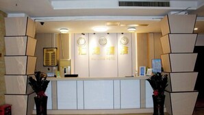 Uma receção de hotel com design moderno, apresentando um relógio, um balcão de receção e um letreiro com o nome do hotel.