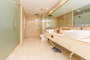 Casa de banho moderna com um espelho grande, uma sanita branca e cabine de duche em vidro.