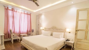 Quarto com uma cama grande, mesas de cabeceira, uma cadeira, escrivaninha e guarda-roupa.