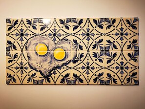 Parede com padrão de azulejos decorativos, apresentando um coração central com dois círculos amarelos.
