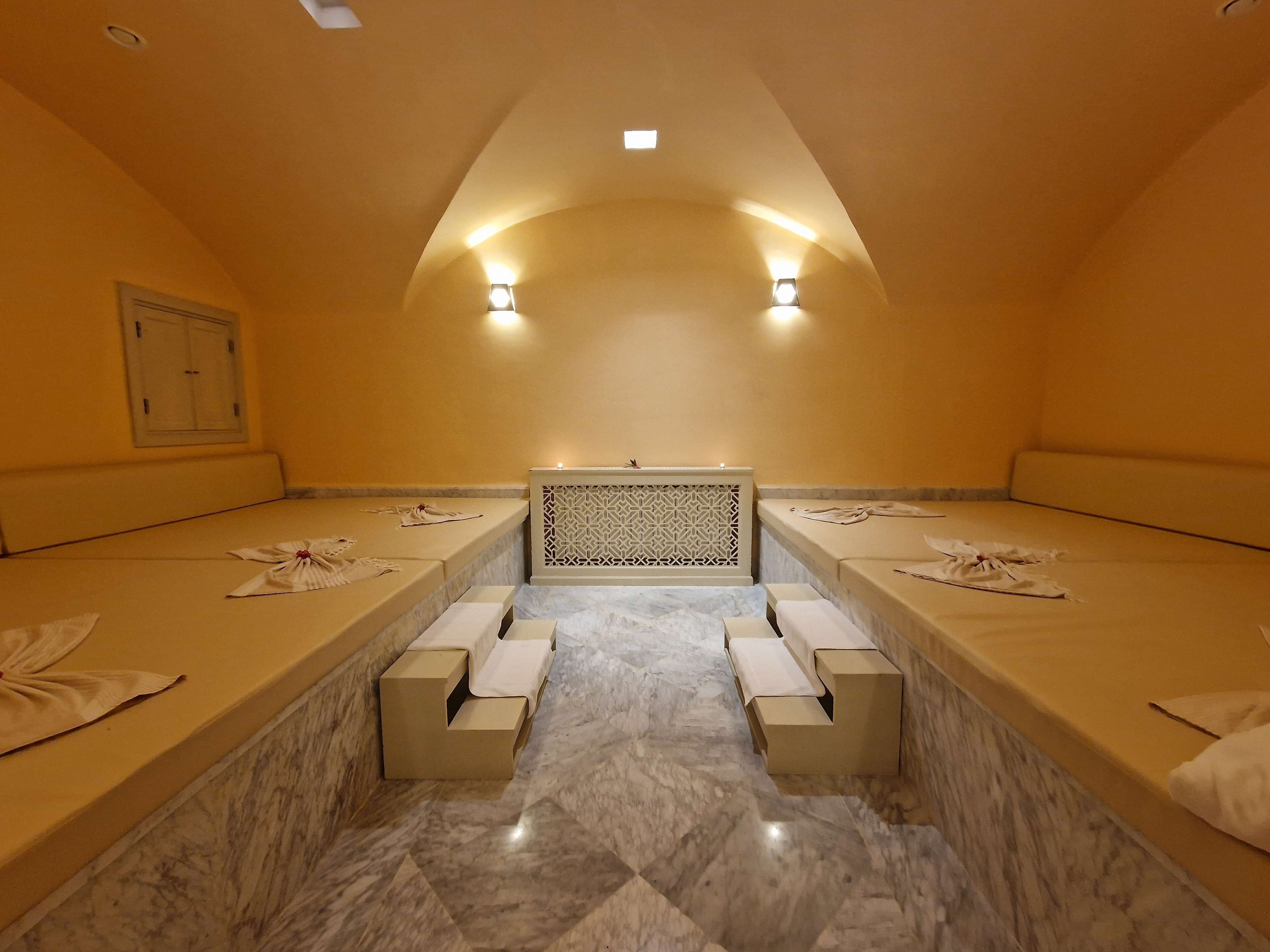 Um espaço de spa com duas mesas de massagem, um painel decorativo na parede e uma luminária no teto.