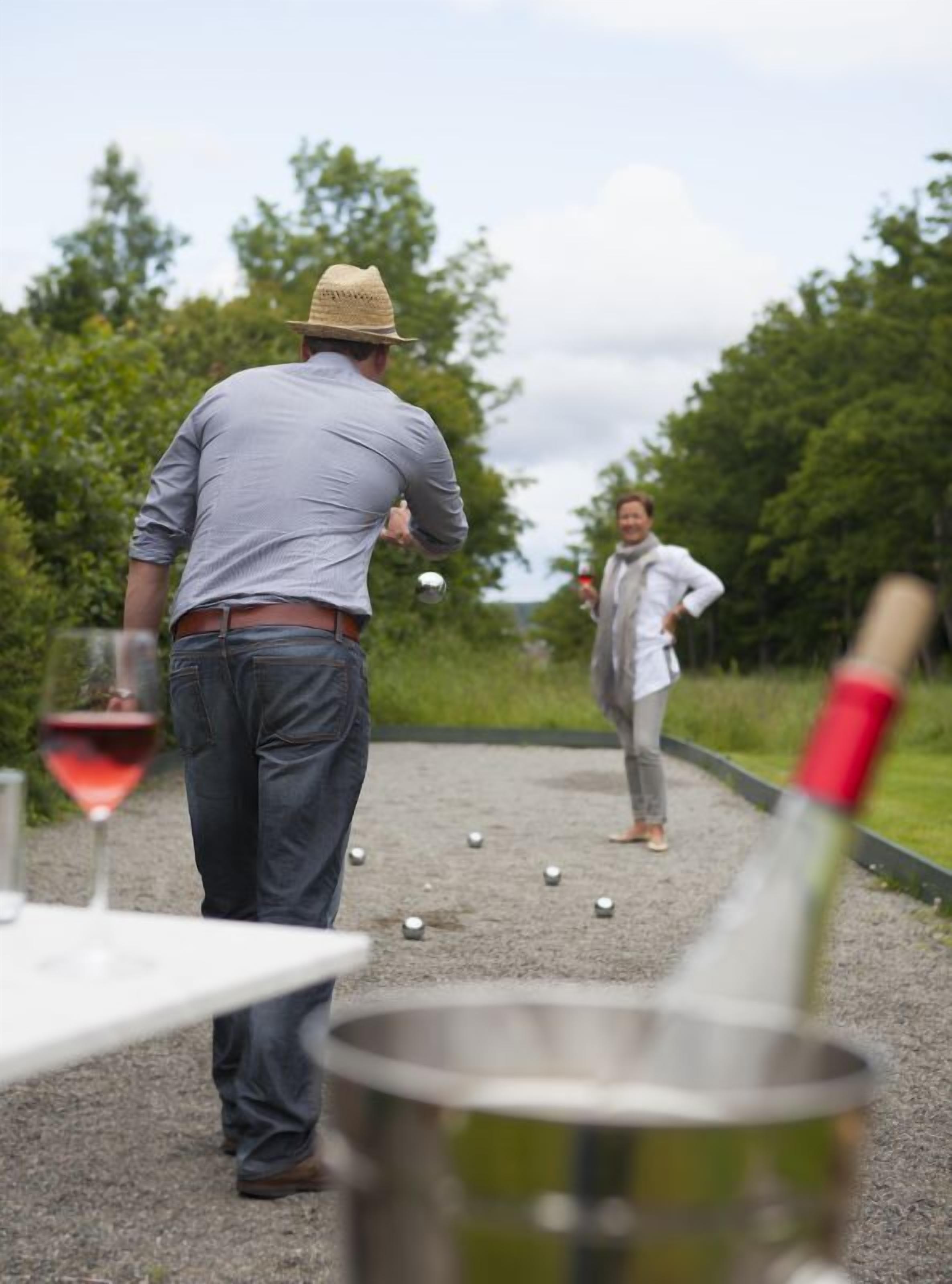 Um homem joga croquet com uma mulher num parque.