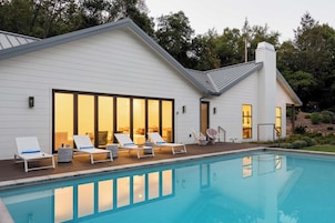 Uma casa moderna com piscina, fachada branca e grandes janelas.