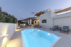 Uma área moderna de piscina ao ar livre com espreguiçadeiras e um bar.