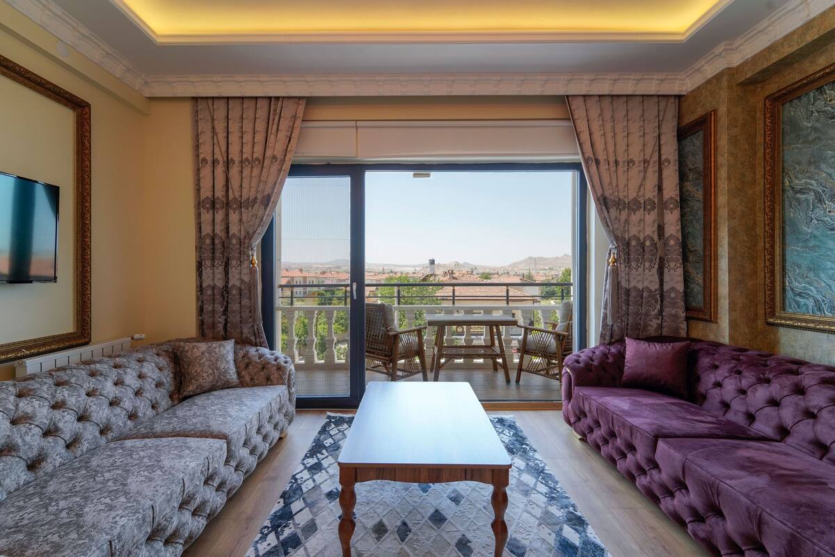 Sala de estar com sofá, mesa e varanda com vista.