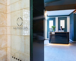 Uma receção com uma placa a dizer "Axis Porto Club" e um homem a trabalhar no balcão.