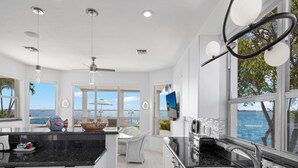 Cozinha moderna com uma ilha grande, área de refeições e vista para o mar.