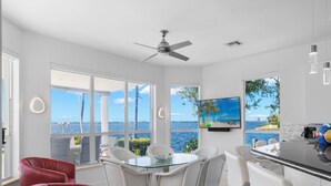 Uma cozinha moderna com uma grande janela com vista para o mar, um ventilador de teto e uma televisão de tela plana na parede.