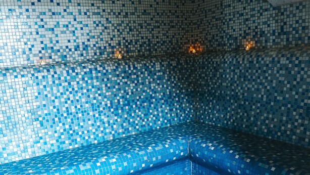 Piscina com azulejos de mosaico azul e teto inclinado.