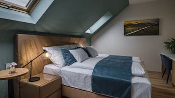 Quarto moderno com claraboia, uma cama com cobertor azul, mesa de cabeceira com abajur e um quadro na parede.
