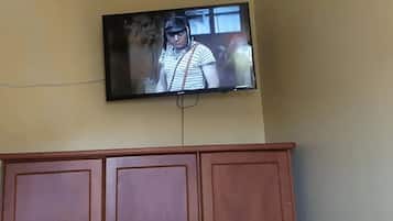 Uma televisão fixada na parede, acima de um armário de madeira.