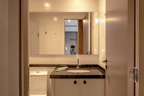 Casa de banho moderna com sanita branca, lavatório com bancada preta e espelho em cima do lavatório.