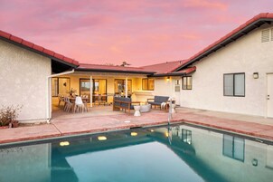 Uma área de piscina com espaço para refeições e um terraço coberto.