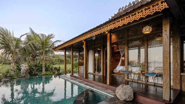 Uma área à beira da piscina com deck de madeira, espreguiçadeiras e vista para a piscina.