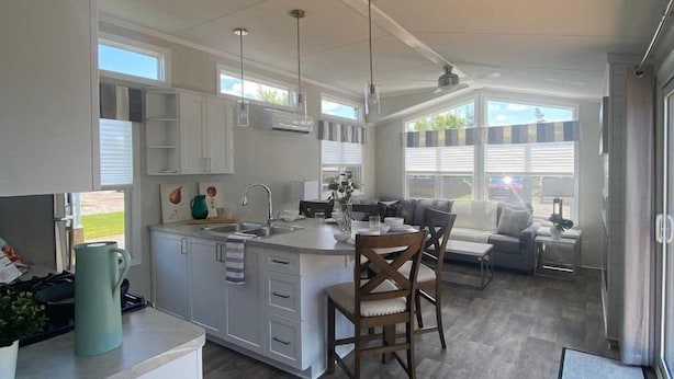 Uma cozinha espaçosa com ilha central, luminárias pendentes e vista para o exterior.