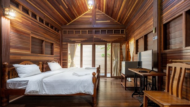 Quarto de cabana de madeira com cama, escrivaninha e televisão.