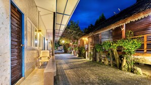 Um caminho de pedras estreito, ladeado por edifícios de madeira com janelas amplas e uma galeria coberta.