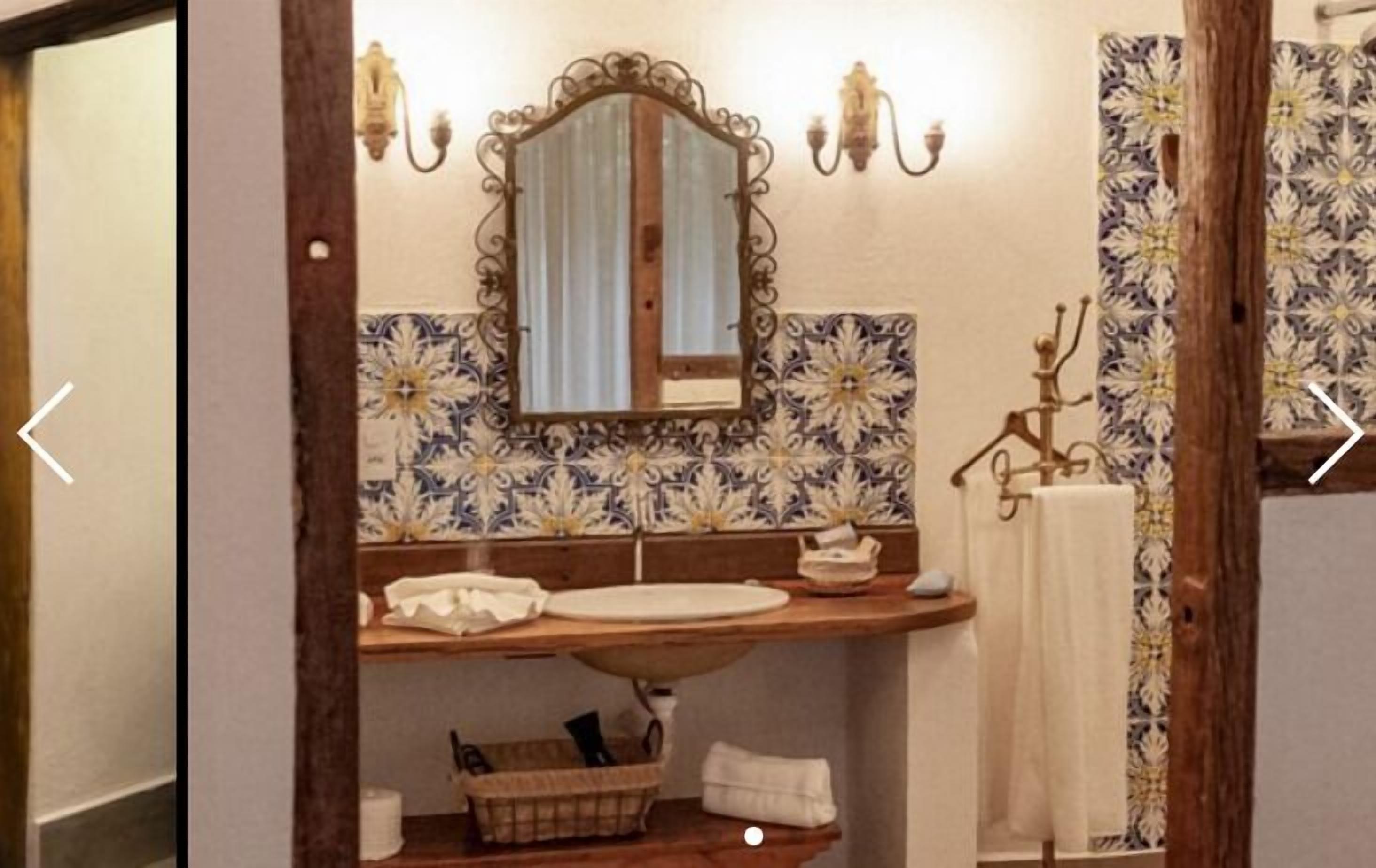 Casa de banho com espelho antigo, lavatório e porta-toalhas.