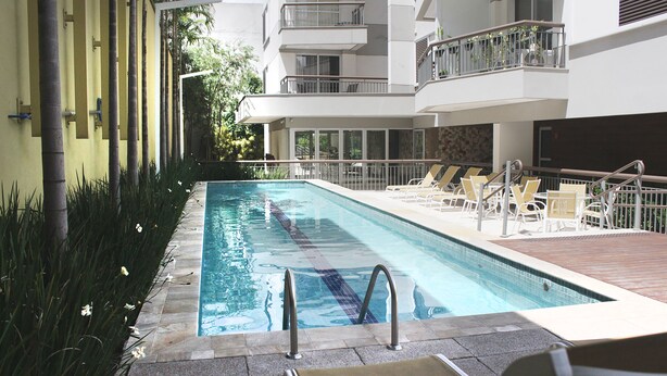 Piscina com uma pista demarcada, rodeada por espreguiçadeiras e um deck de madeira.