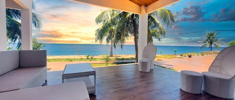 Uma área de estar coberta ao ar livre com vista para a praia e o oceano.