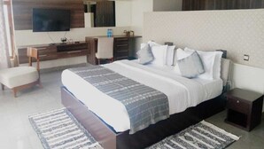 Quarto moderno com uma cama grande, televisão de tela plana na parede, escrivaninha e uma cadeira.