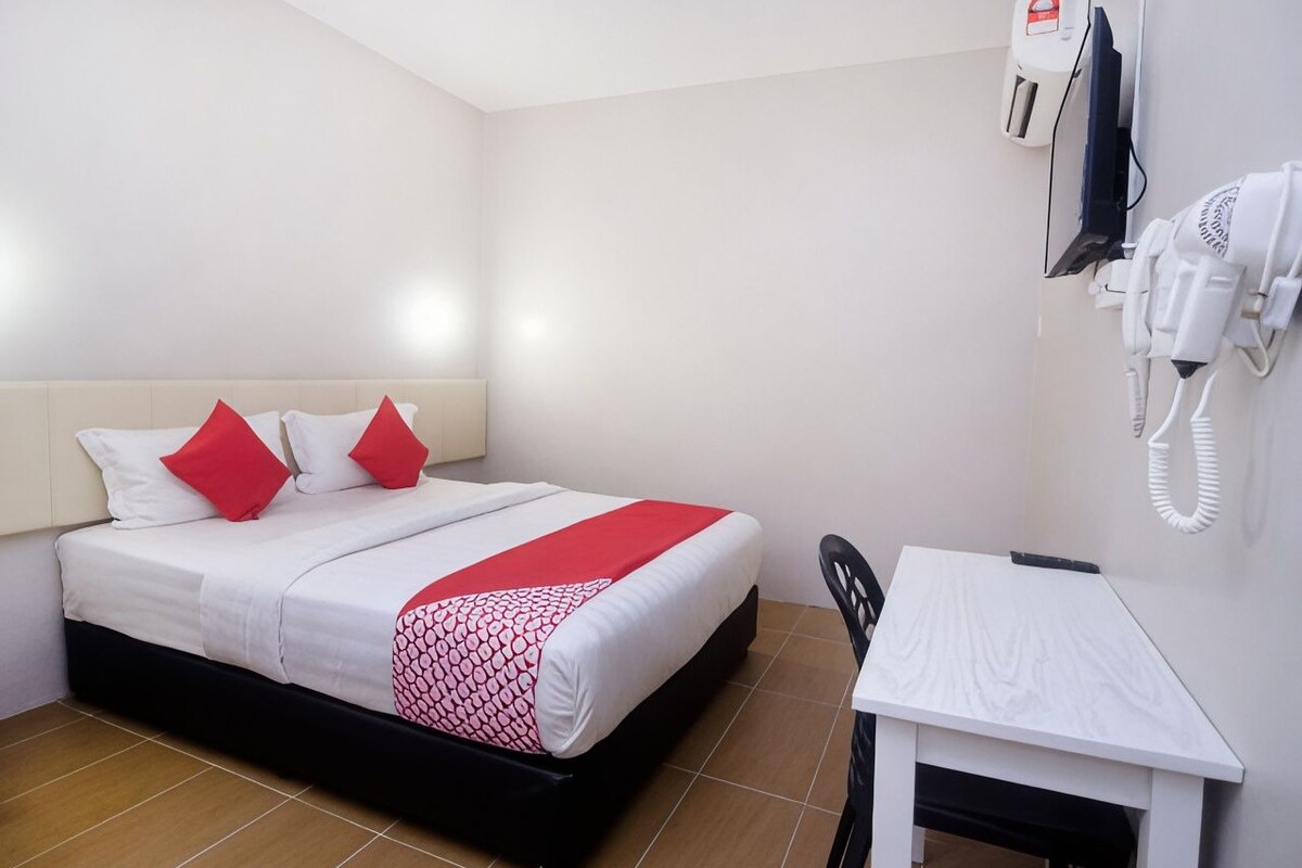 Quarto de hotel com cama, escrivaninha e telefone.