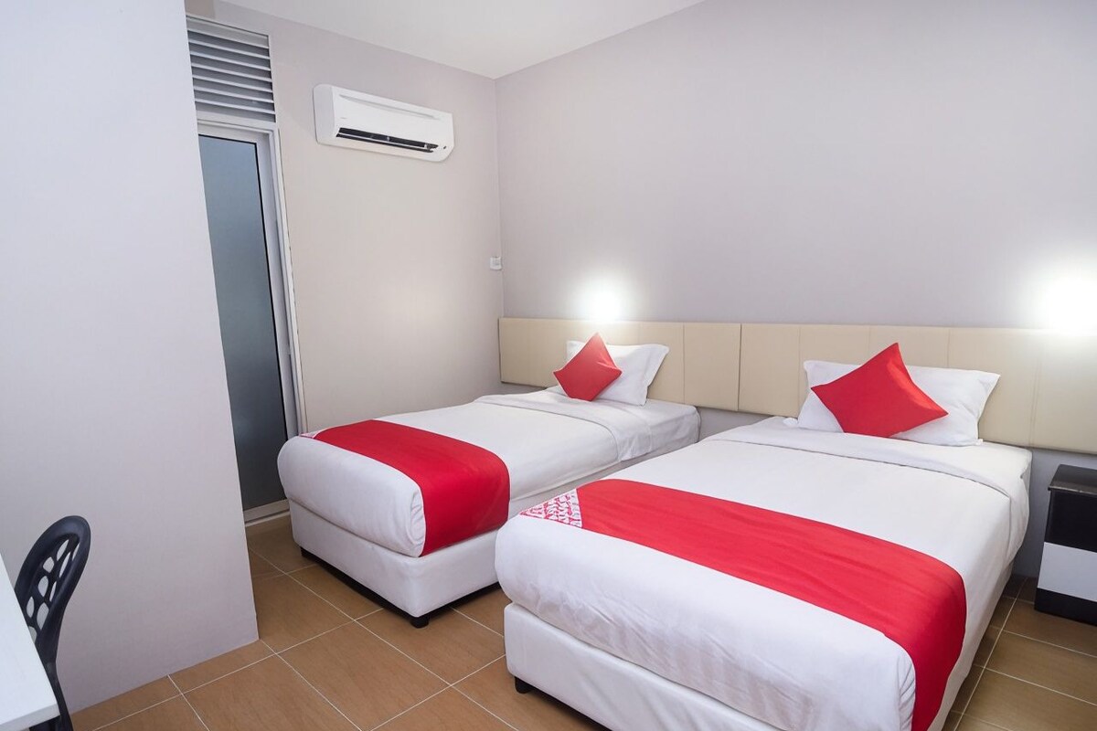 Quarto de hotel com duas camas, uma escrivaninha e um aparelho de ar condicionado.