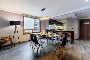 Uma sala de jantar moderna com uma mesa de vidro, cadeiras pretas e um abajur.