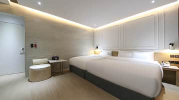 Quarto de hotel moderno com uma cama grande, mesas de cabeceira, um espaço de estar pequeno e um guarda-roupa.