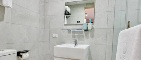 Casa de banho moderna com sanita, lavatório e cabine de duche em vidro.