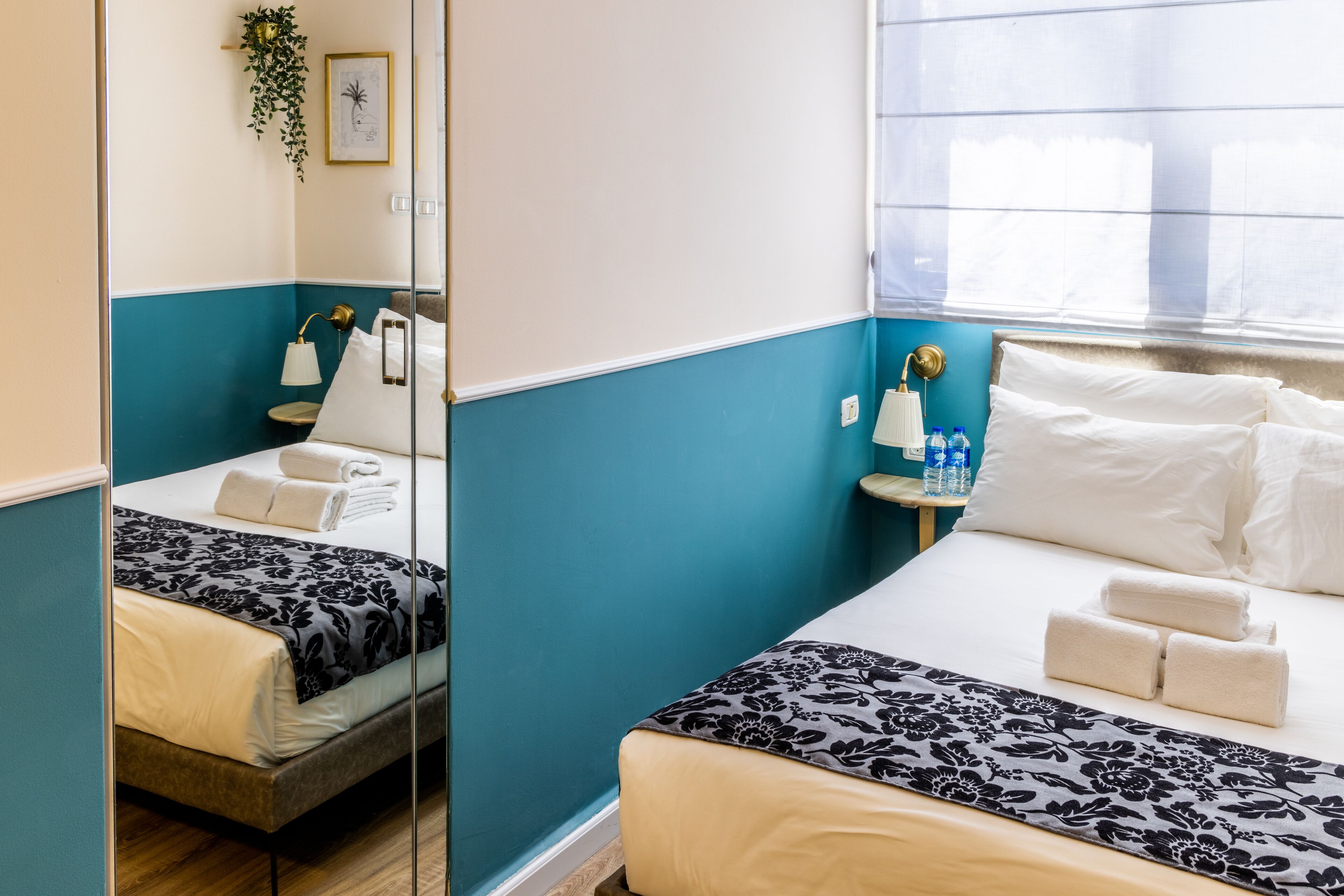 Quarto de hotel com cama, mesa de cabeceira e janela com cortinas.