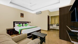 Quarto de hotel com cama, escrivaninha, cadeira, sofá, ventoinha no teto, ar condicionado e televisão.