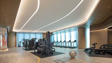 Academia moderna com equipamentos de cardio, máquinas de peso e uma bola de exercícios grande.