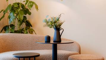 Uma sala de estar moderna com uma mesa redonda, um abajur, um vaso de planta e um sofá.