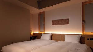 Quarto de hotel com duas camas, uma mesa de cabeceira com abajur e um espelho grande na parede.
