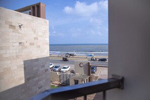 Vista da praia a partir de uma varanda com parede de pedra e guarda-corpo de metal.