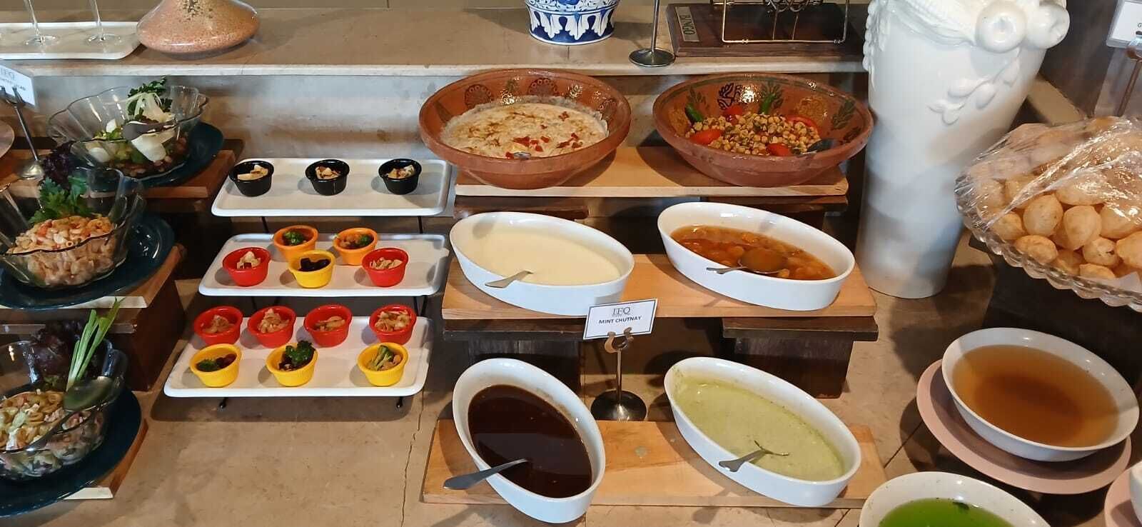 Buffet com diversos pratos, incluindo saladas, sopas e sobremesas.