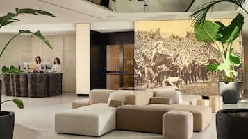 Um lobby moderno com balcão de recepção, área de estar e uma grande obra de arte na parede.