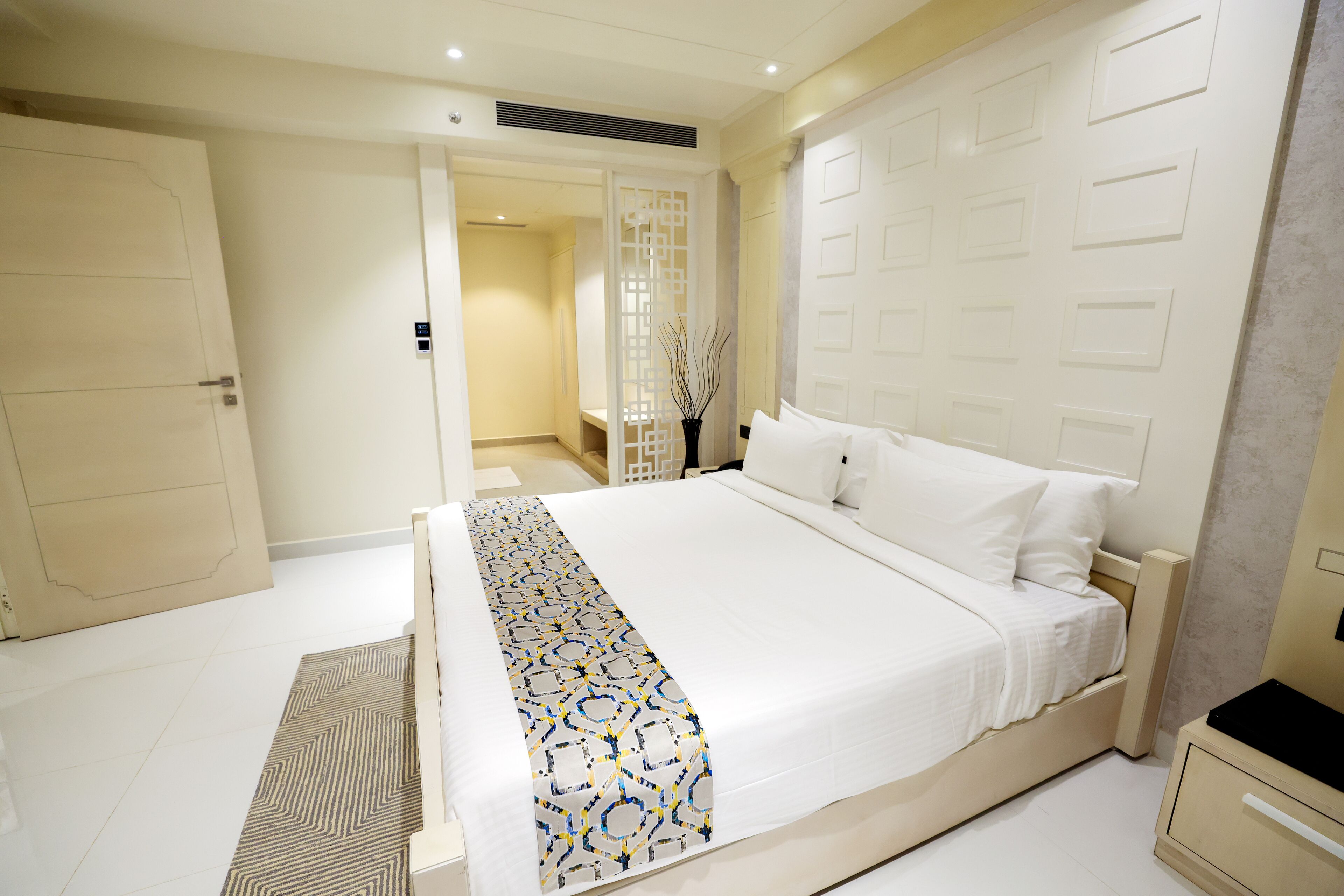 Quarto de hotel moderno com uma cama grande, uma mesa de cabeceira e um guarda-roupa.