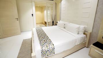 Quarto de hotel moderno com uma cama grande, uma mesa de cabeceira e um guarda-roupa.
