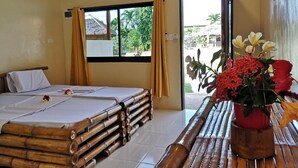 Quarto com cama, janela, ventilador de teto e mesa com planta em vaso.