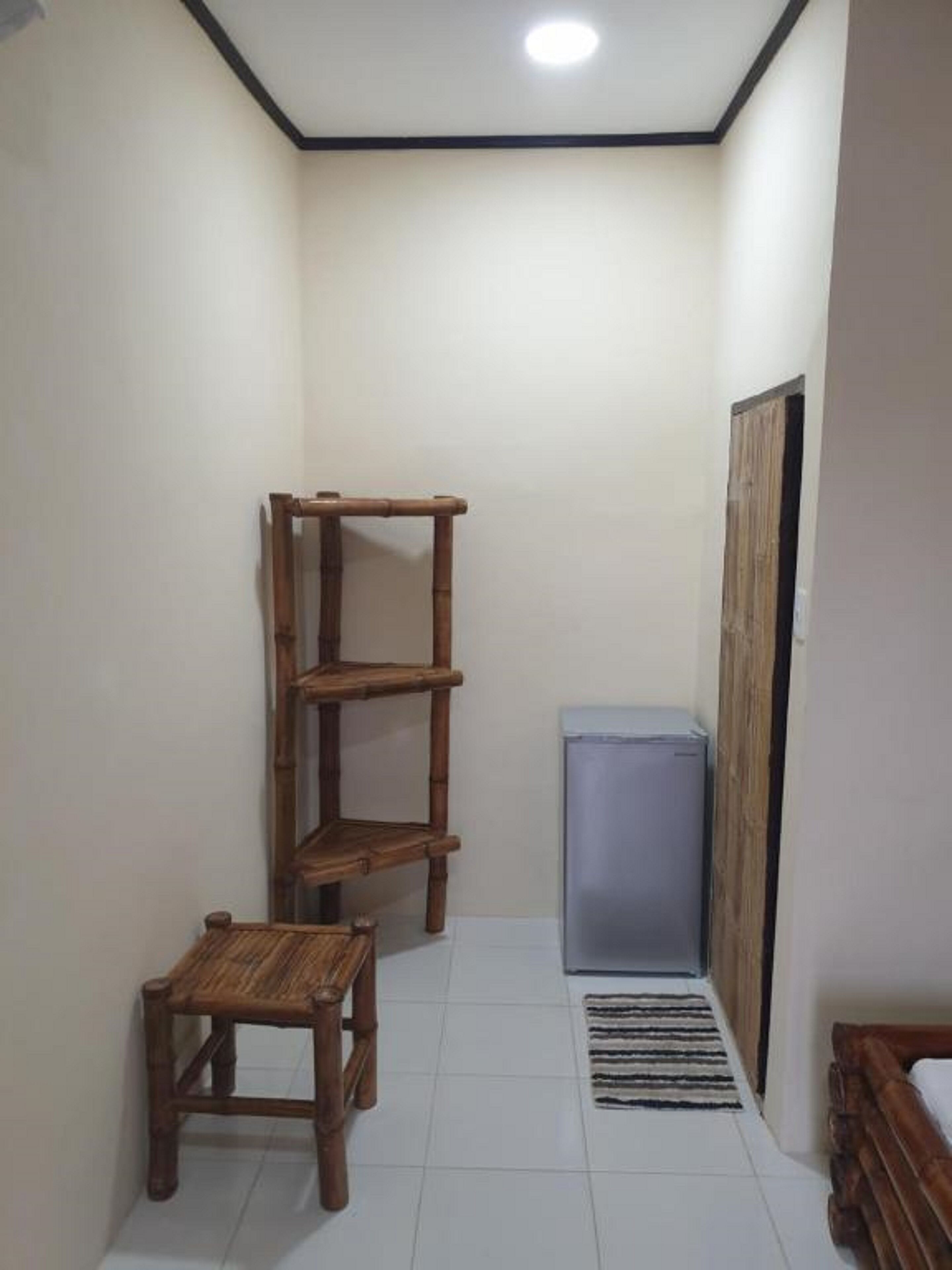 Quarto pequeno e limpo com uma prateleira de madeira, uma mesinha, um radiador e uma cama.
