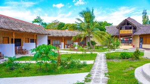 Um resort com edifícios de telhado de palha, um caminho central e vegetação exuberante.