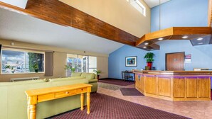 Um quarto espaçoso com sofá verde, um banco de madeira e um espaço bar com uma planta.