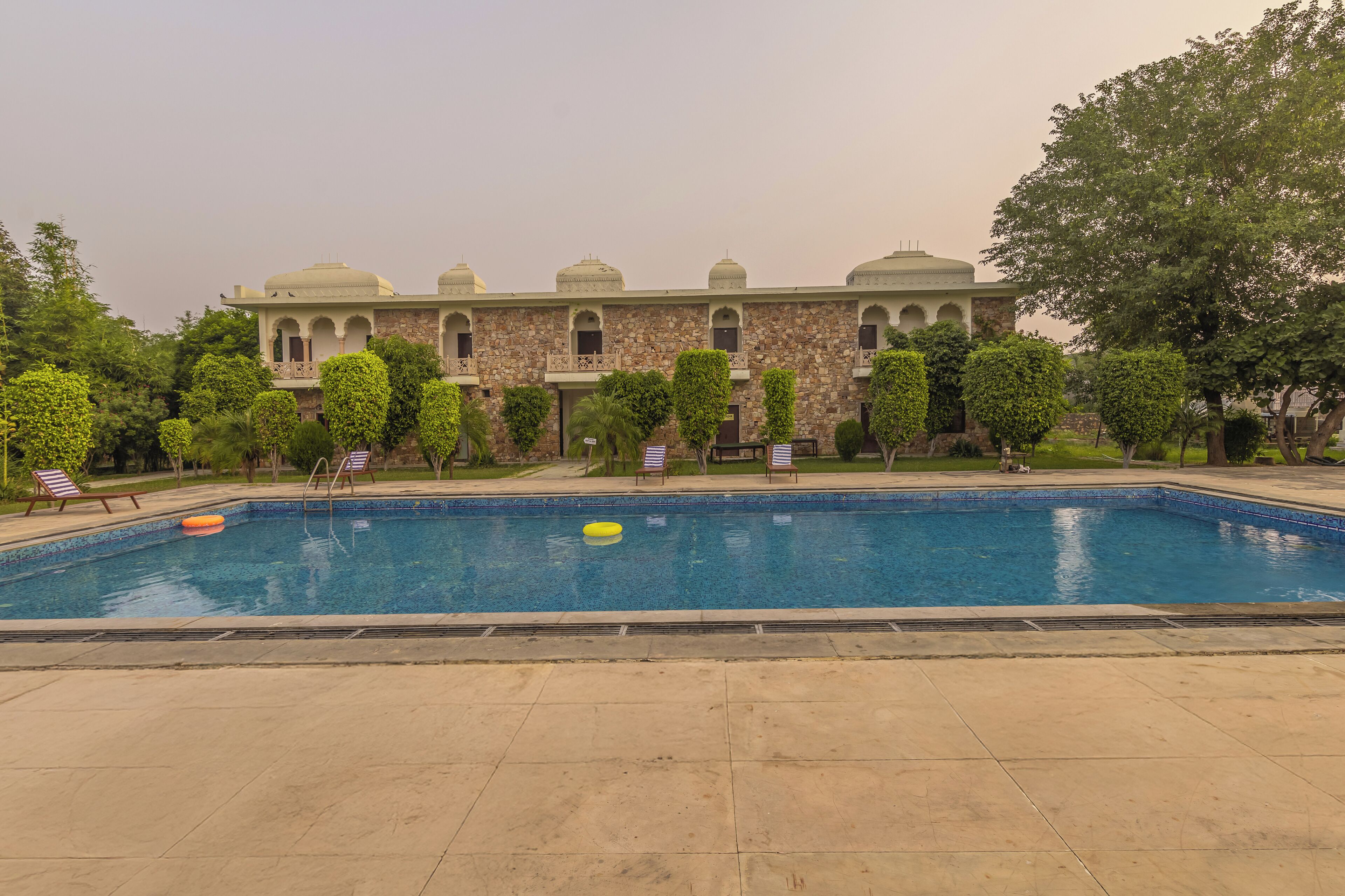 Uma piscina com espreguiçadeiras e um edifício com cúpulas ao fundo.